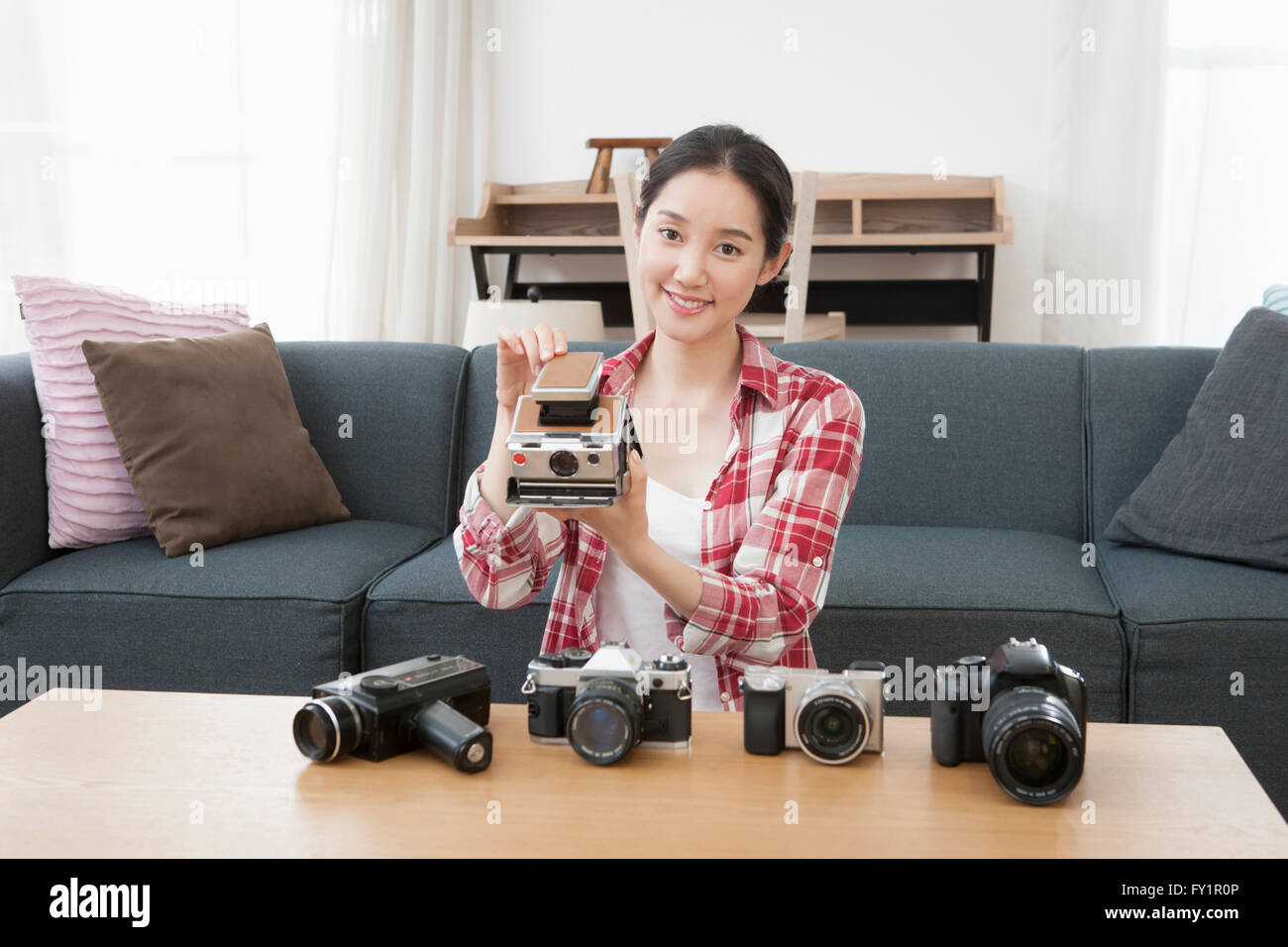 Portrait of young smiling woman with various cameras staring at front ...
