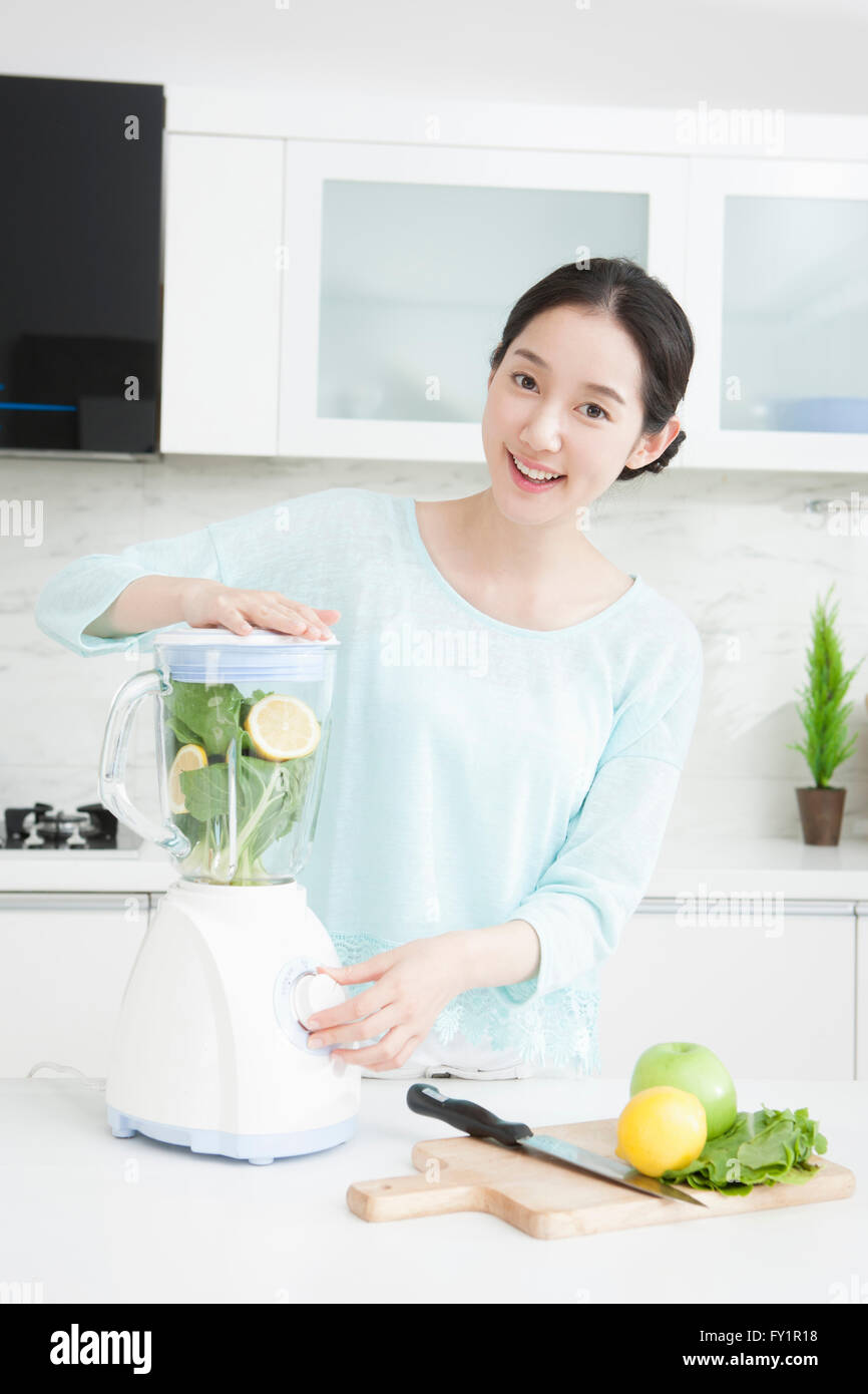 Portrait of young smiling woman with a blender full of vegetables in ...
