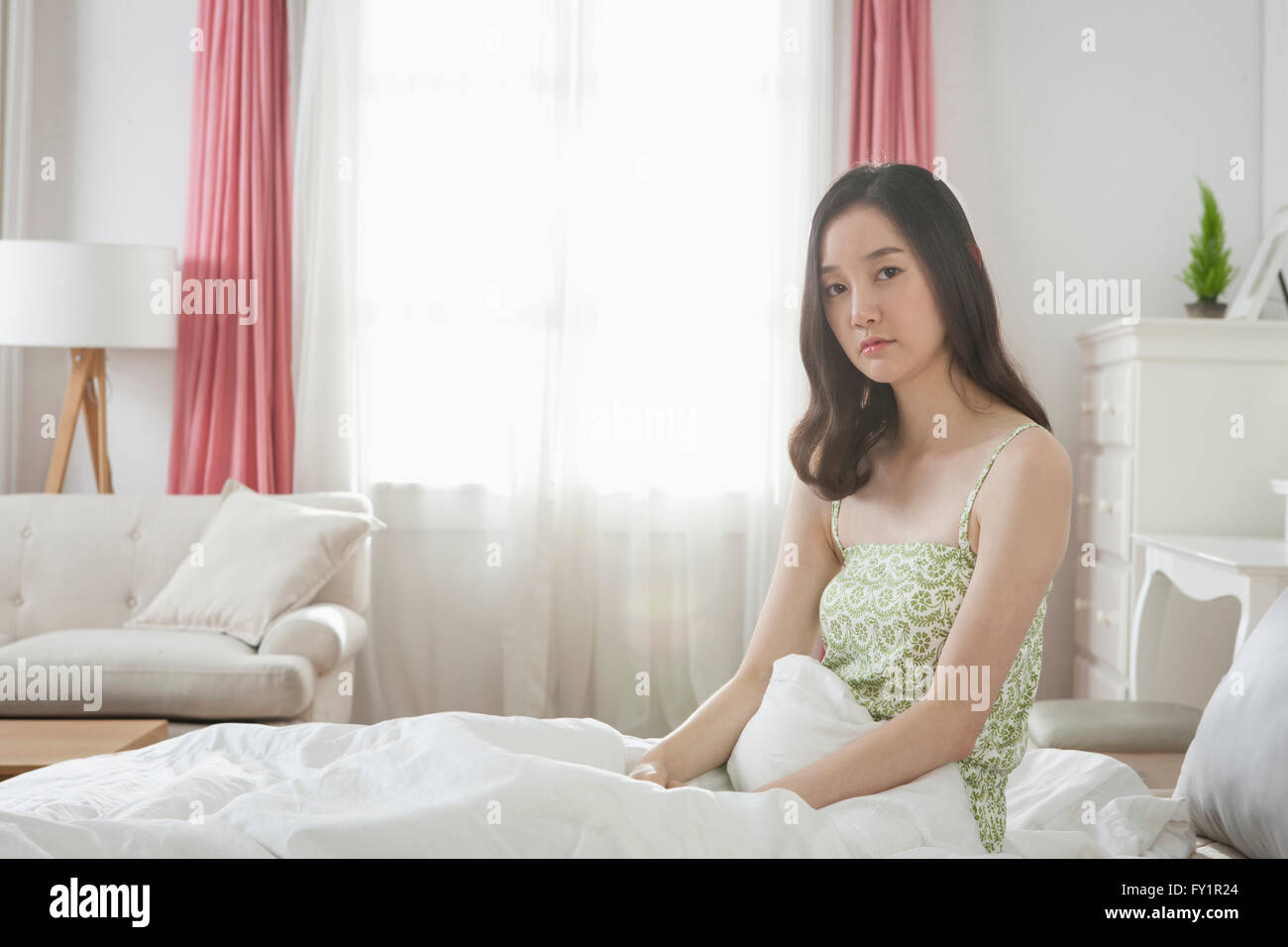 Young woman sitting in bed staring at front Stock Photo - Alamy
