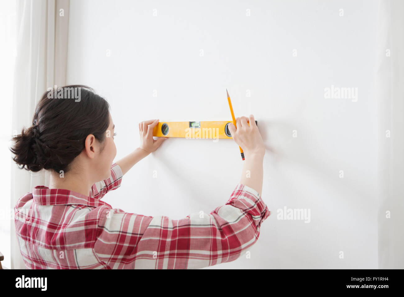 Back of young woman measuring wall with ruler and pencil Stock Photo ...