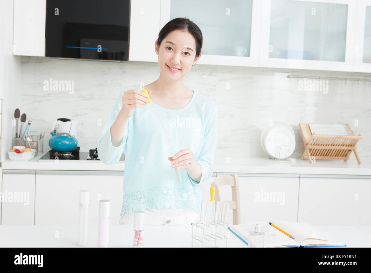 Portrait of young smiling woman doing experiment in kitchen Stock Photo ...