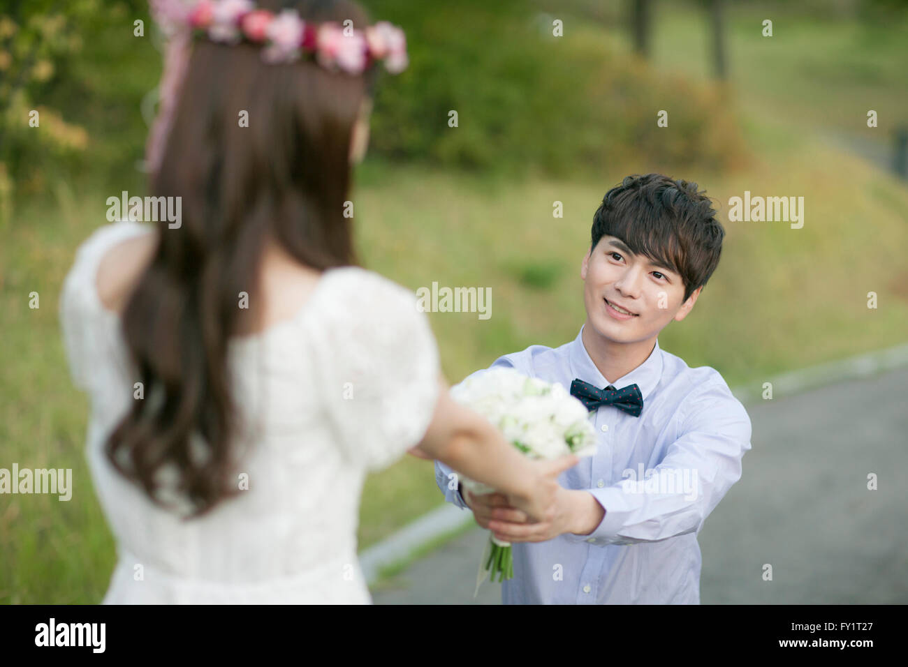Portrait of young smiling wedding couple giving and taking a bouquet at ...