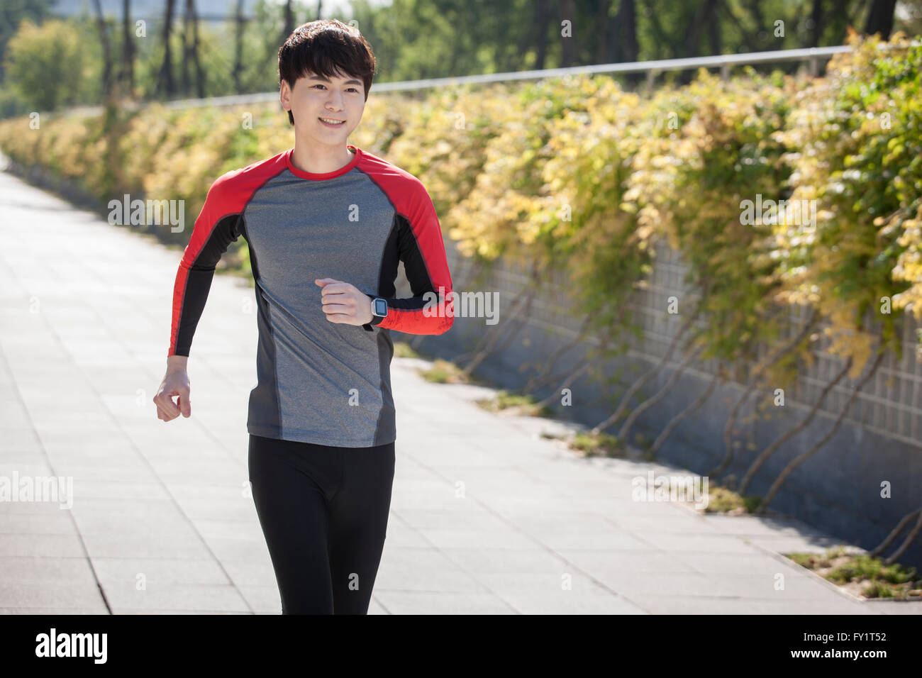 Young smiling man jogging at park Stock Photo - Alamy