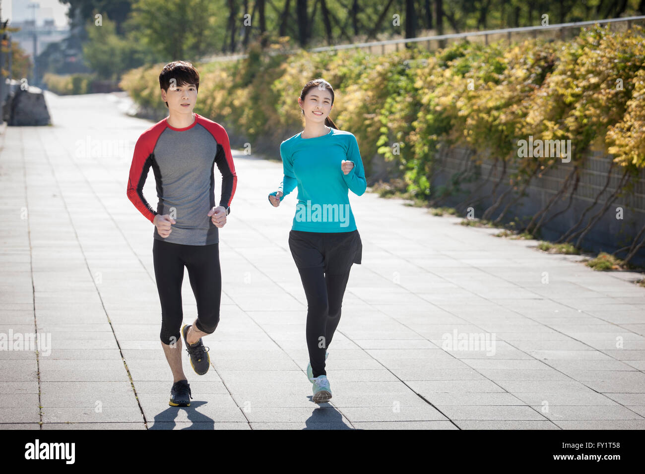 Young smiling couple jogging at park Stock Photo - Alamy