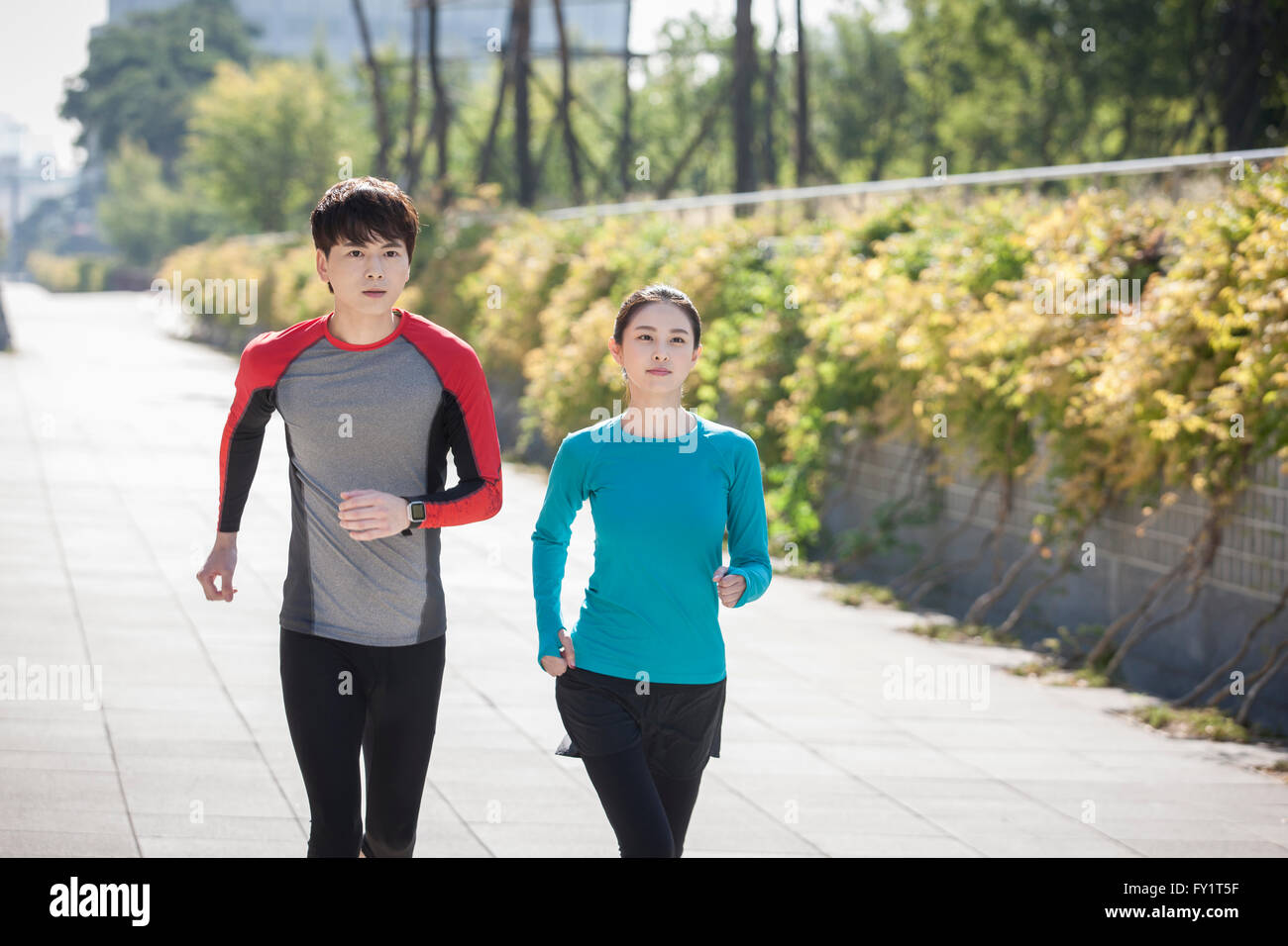 Young smiling couple jogging at park Stock Photo - Alamy