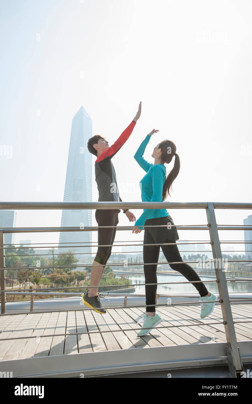 Side view od young smiling couple jumping holding hands face to face ...