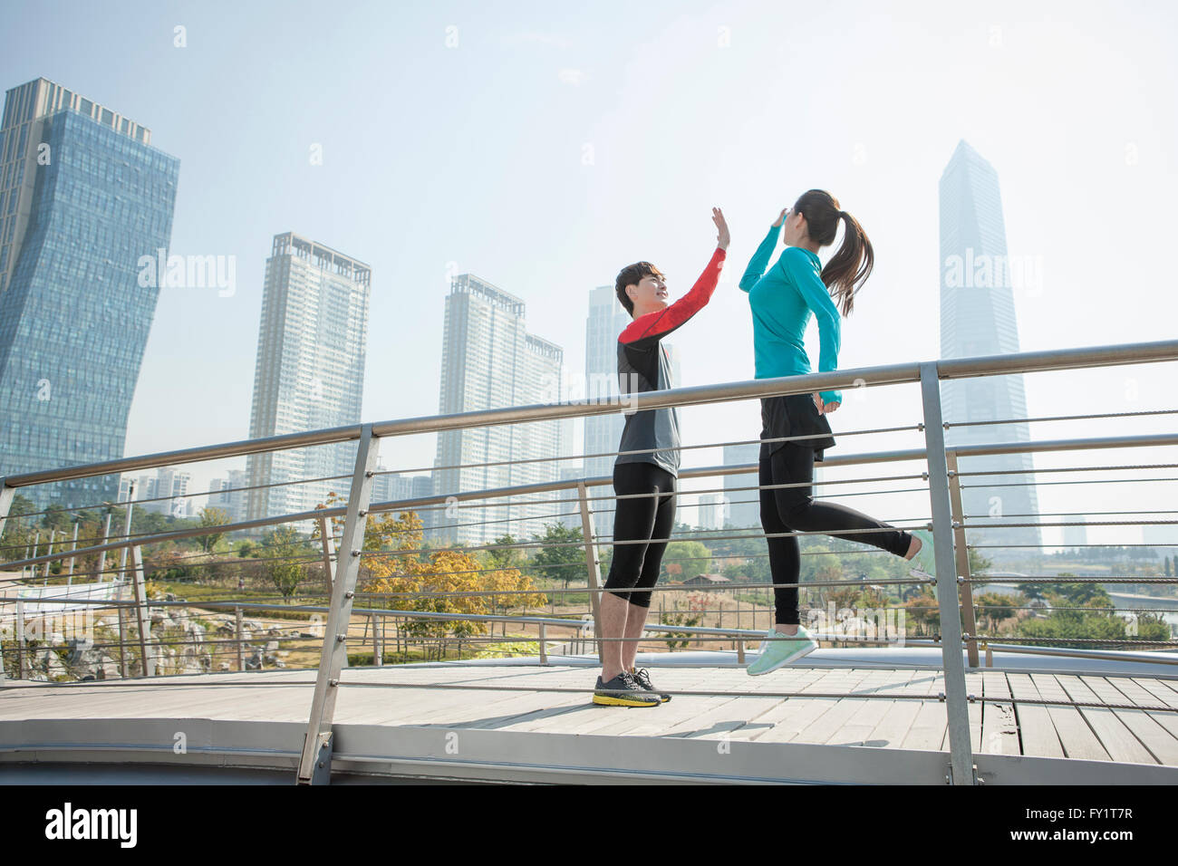 Side view od young smiling couple standing and jumping slapping their ...