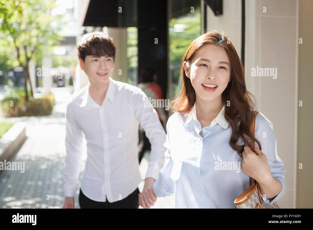 Woman pulling her boyfriend's hand and moving forward at the street ...