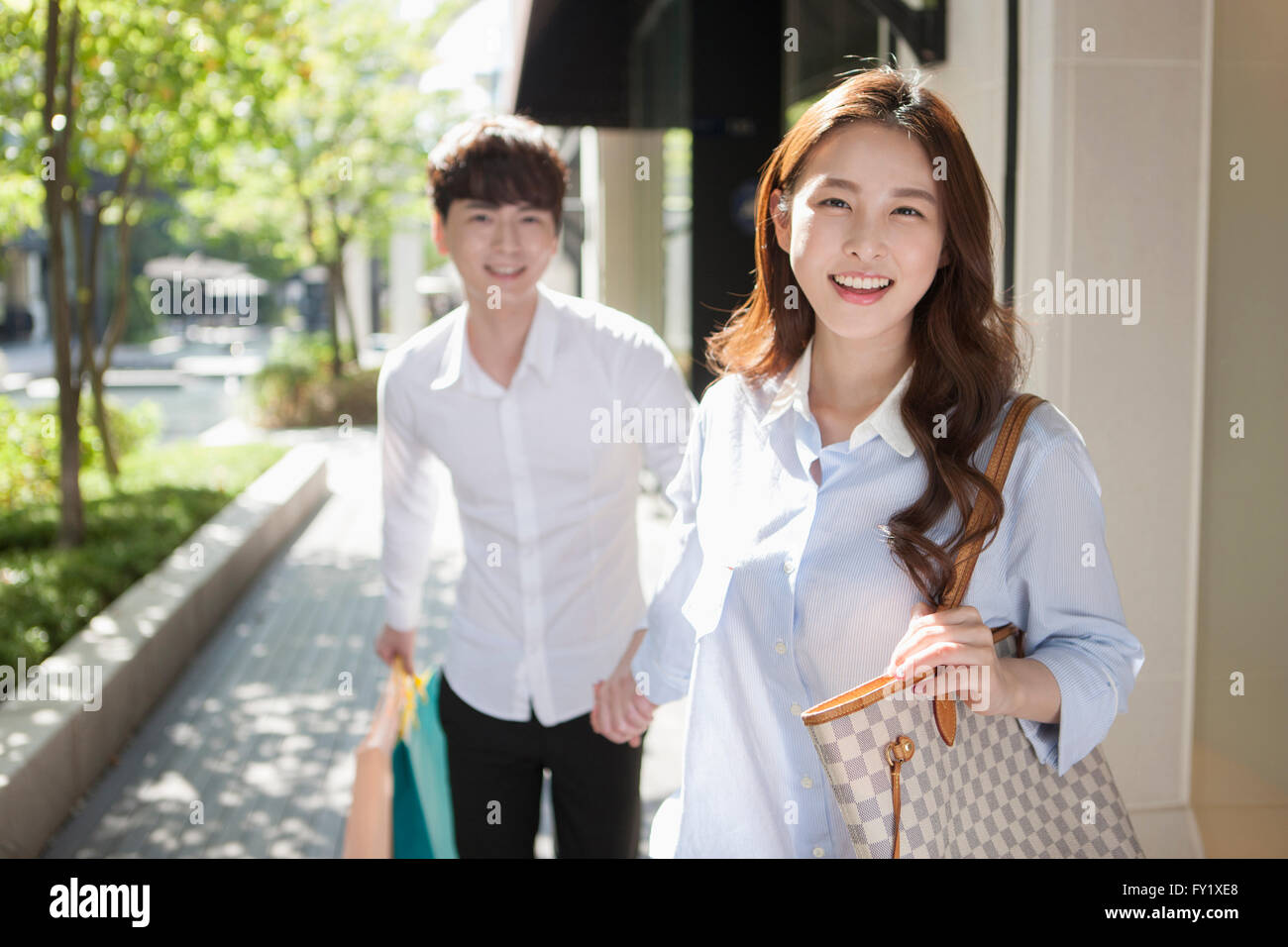 Woman pulling her boyfriend's hand and moving forward at the street ...