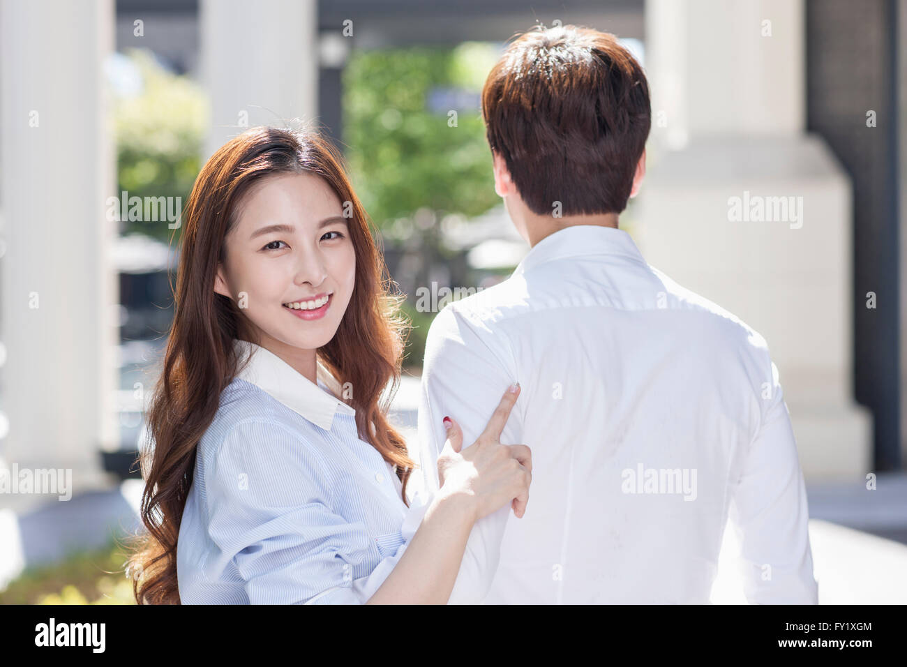Woman staring forward with a smile and holding her boyfriends hand at ...