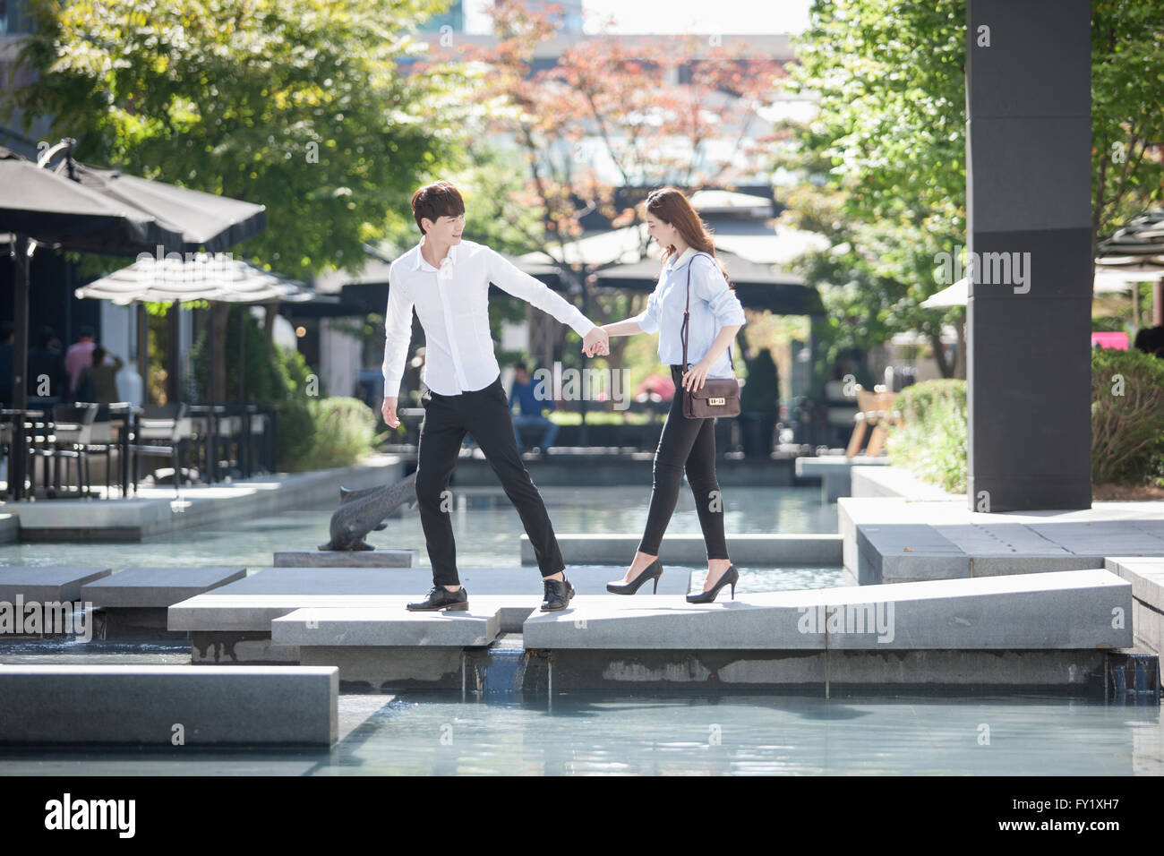 Couple walking on stepping stones hand in hand outside Stock Photo - Alamy