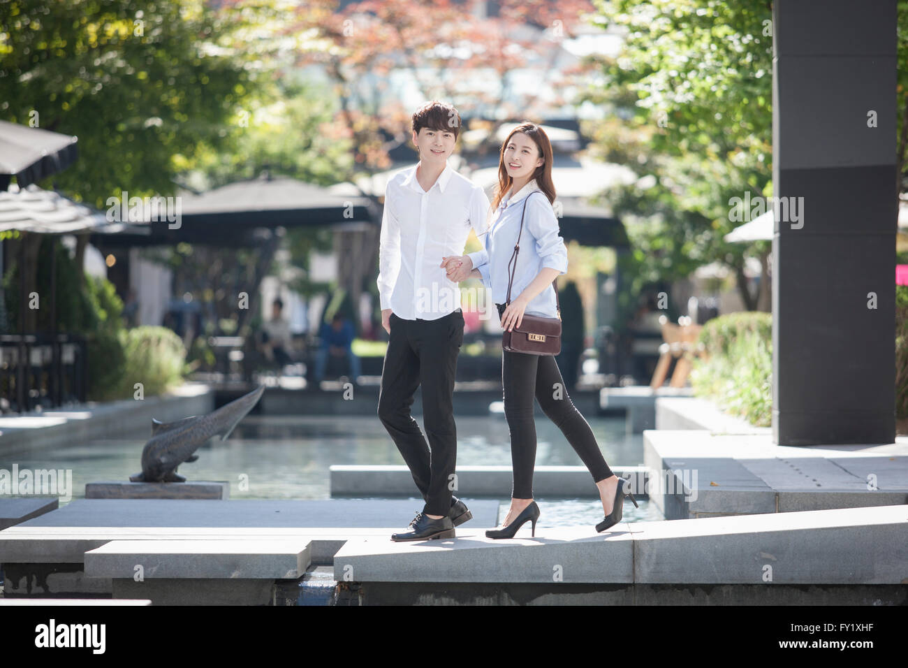 Couple walking on stepping stones hand in hand outside Stock Photo - Alamy