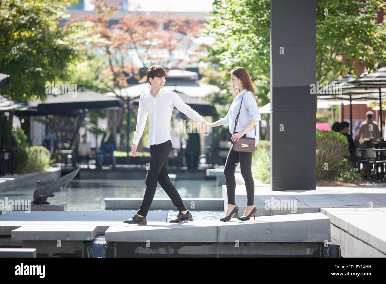 Couple walking on stepping stones hand in hand outside Stock Photo - Alamy