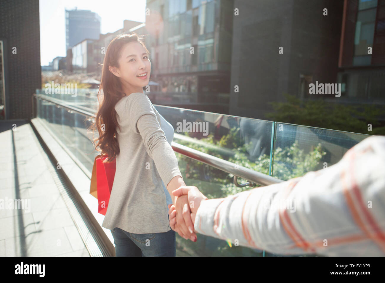 Woman with shopping bags pulling out her boyfriend's hand outside Stock ...