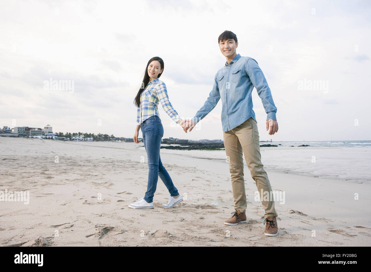 Couple standing hand in hand at the beach Stock Photo - Alamy