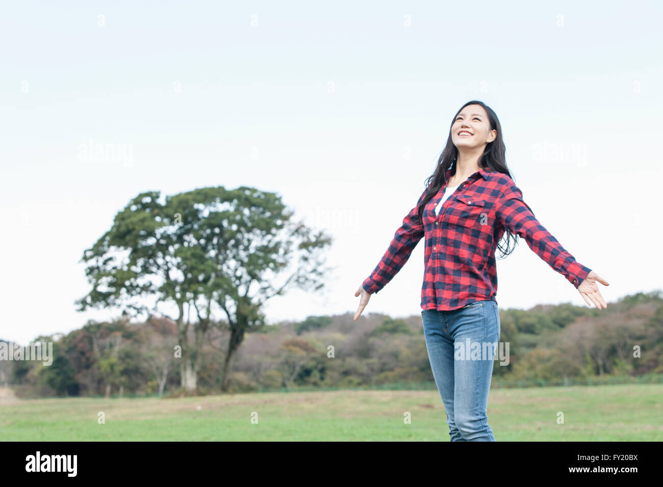 Woman stretching her arms wide and looking up with a smile at the field ...