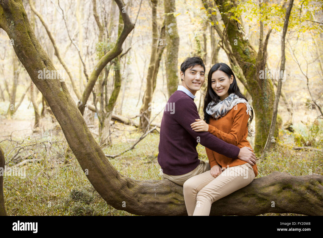 Couple taking a rest on a branch and hugging each other at the forest ...