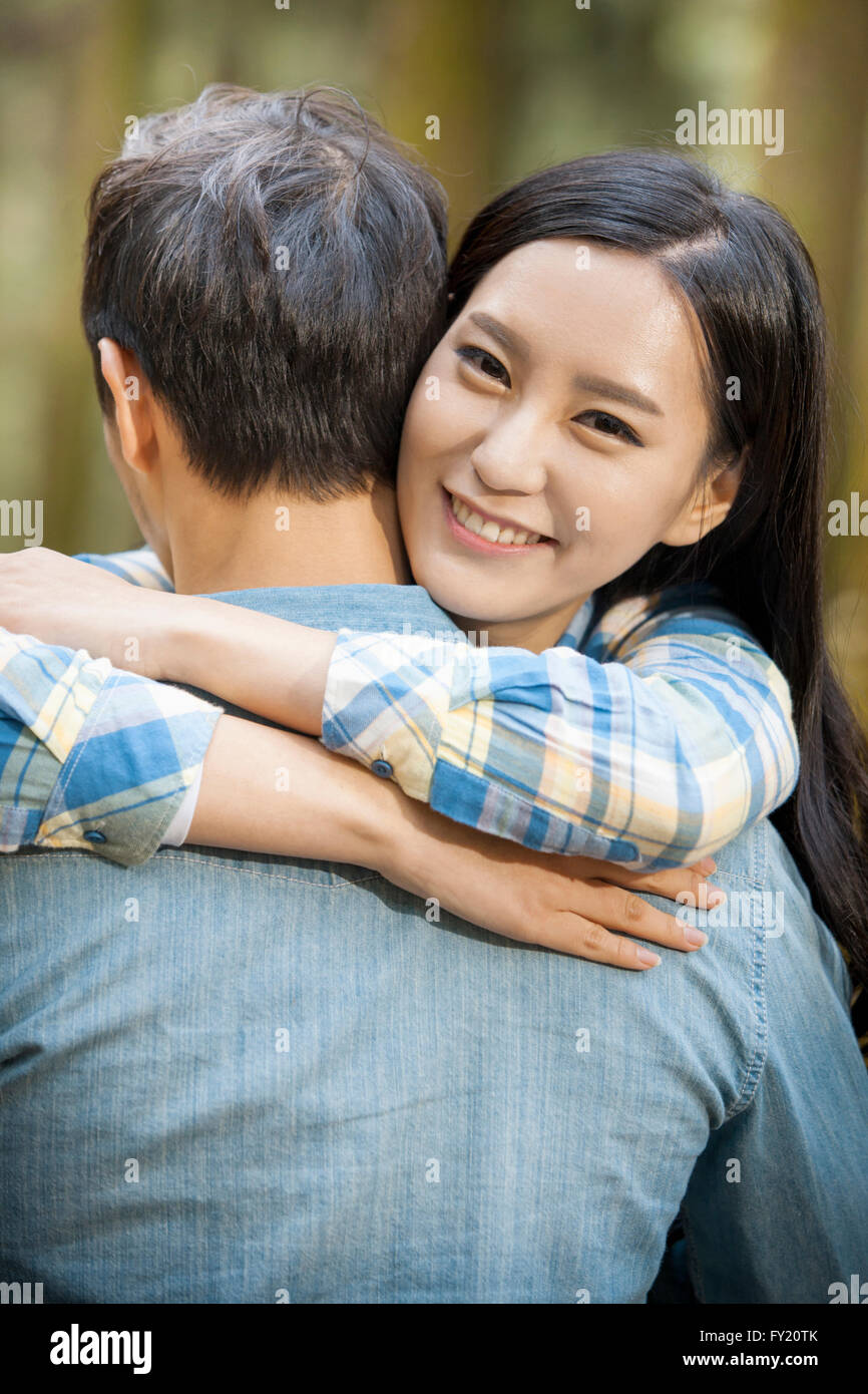 Woman hugging her boyfriend with a smile Stock Photo - Alamy