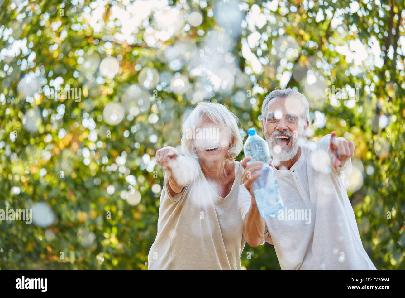Laughing seniors splash happily water with a bottle in summer Stock ...