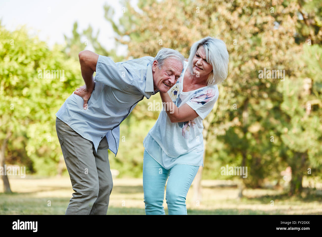 Woman helps old man with back pain in the park in summer Stock Photo ...