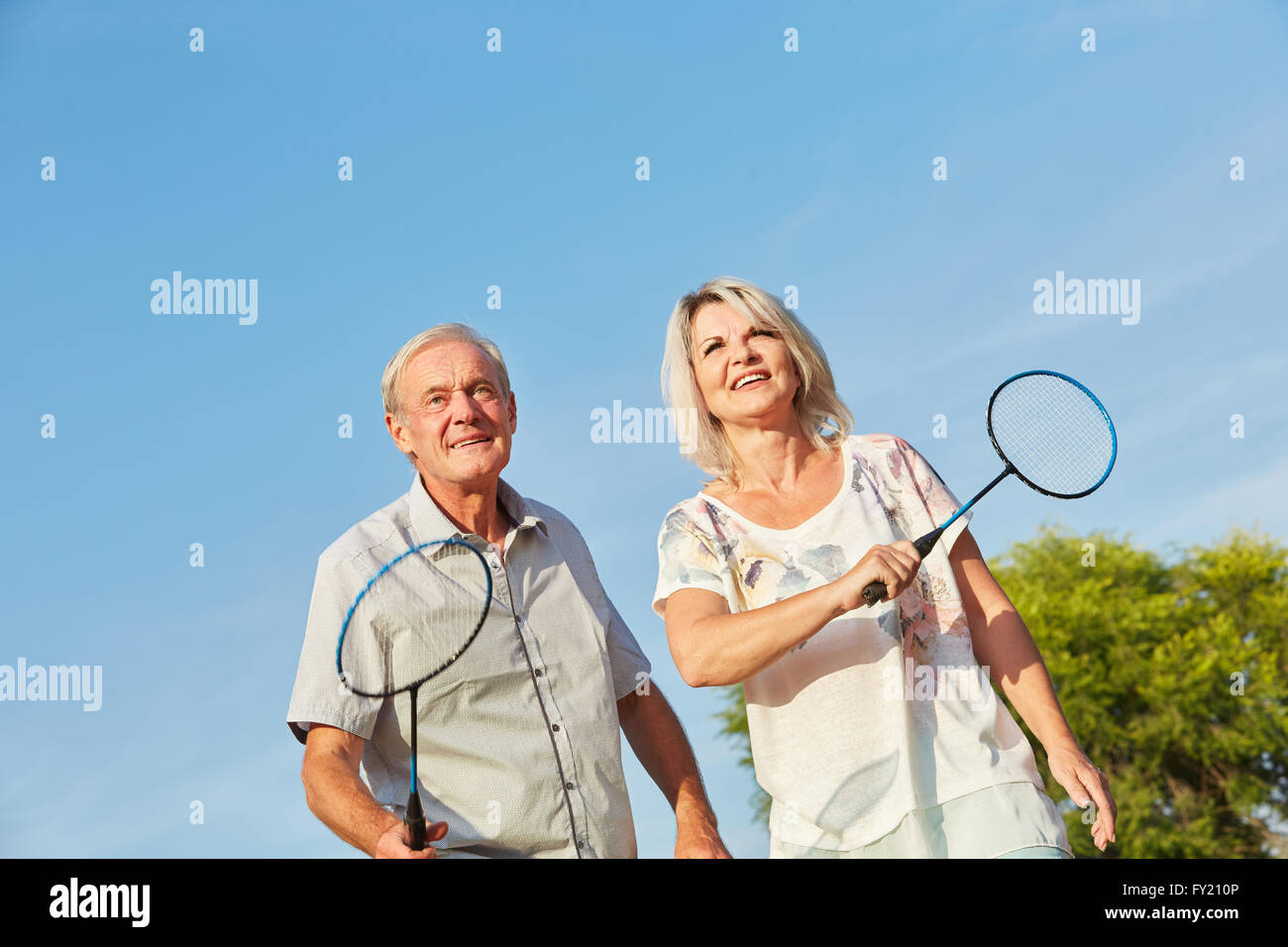 Happy senior citizens playing badminton as a team in summer Stock Photo ...
