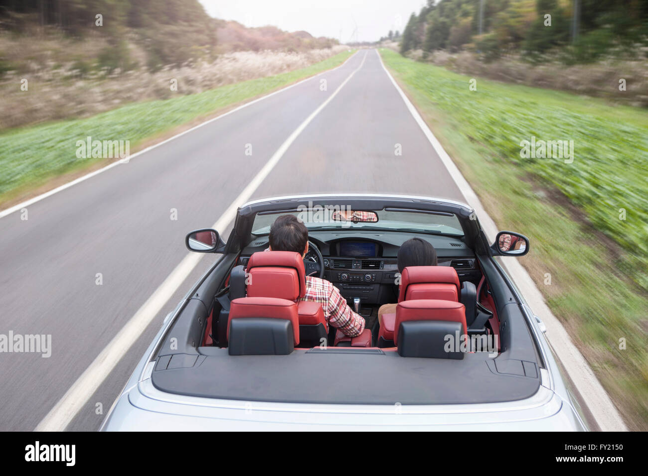 Couple on a convertible car driving on the road Stock Photo - Alamy