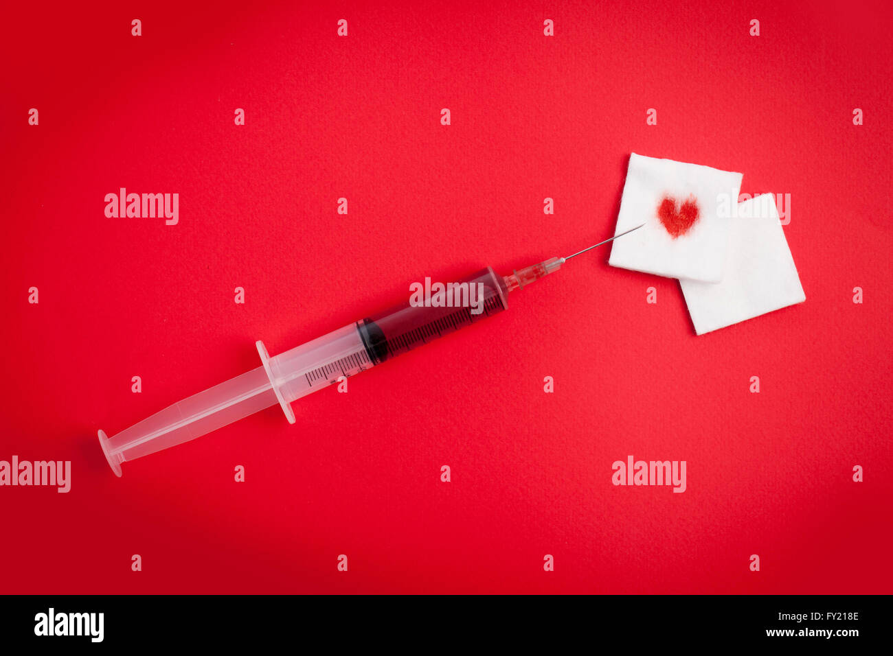 Red heart blood stain on a cotton and an injection filled with blood on ...
