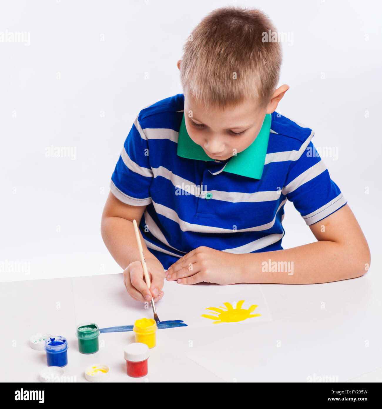 Happy cheerful child drawing with brush in album using a lot of ...