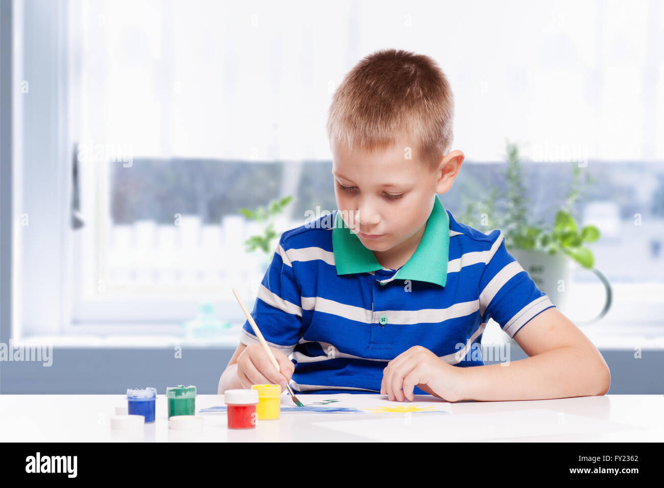 Happy cheerful child drawing with brush in album using a lot of ...
