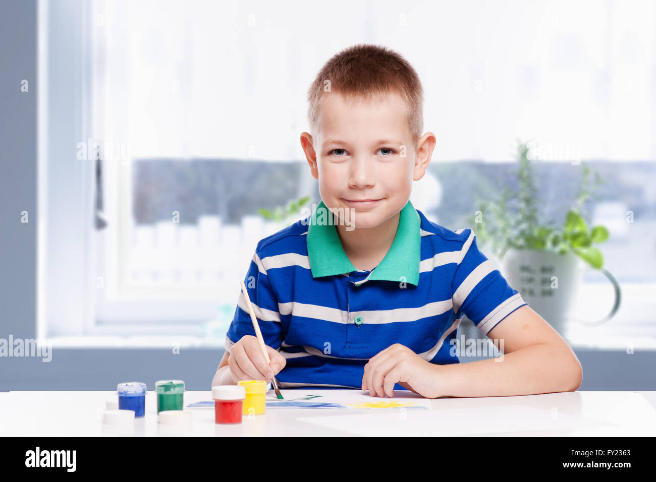 Happy cheerful child drawing with brush in album using a lot of ...