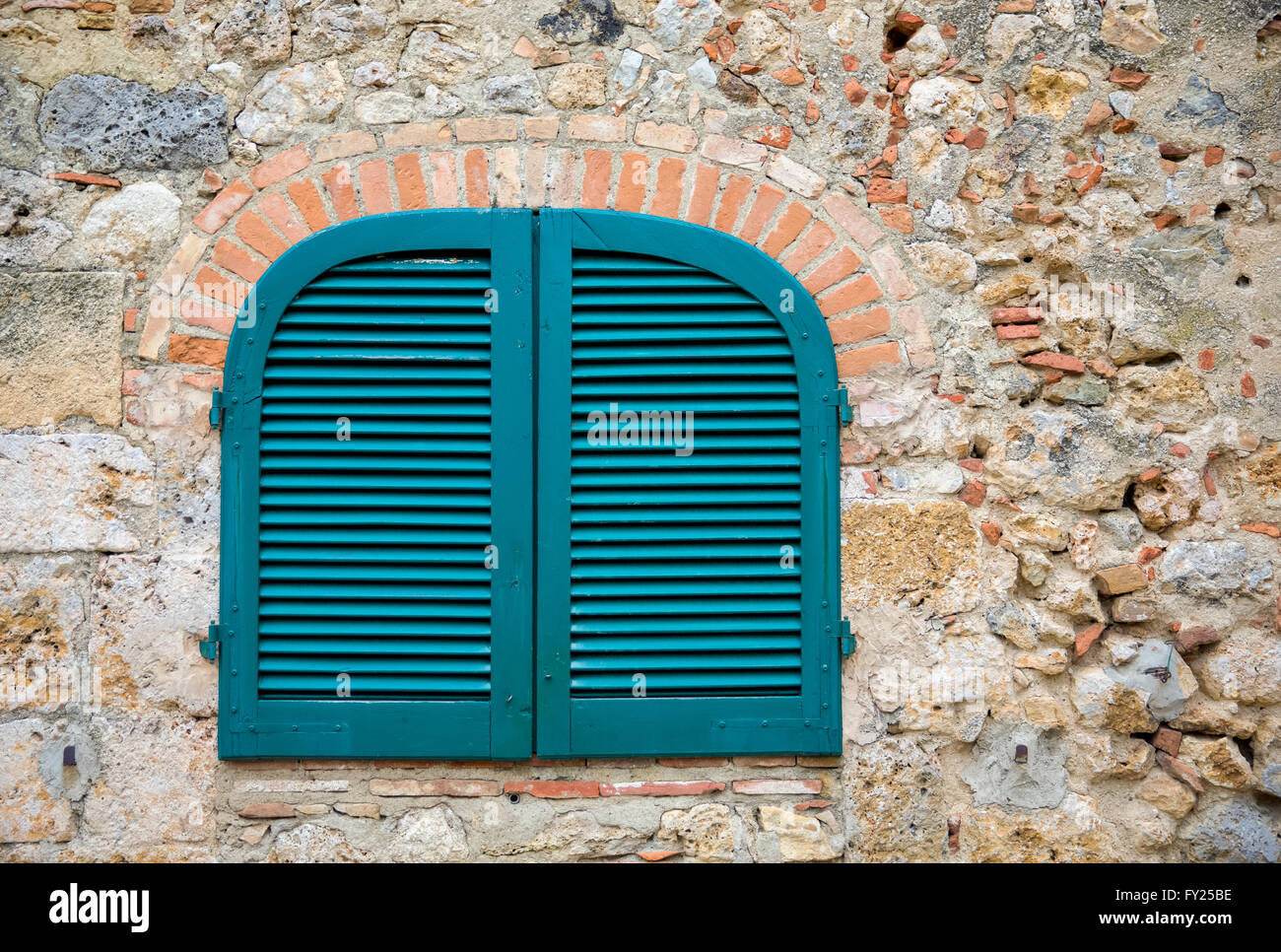 Blue shutters in a medieval stone wall in a Tuscan village in Italy ...
