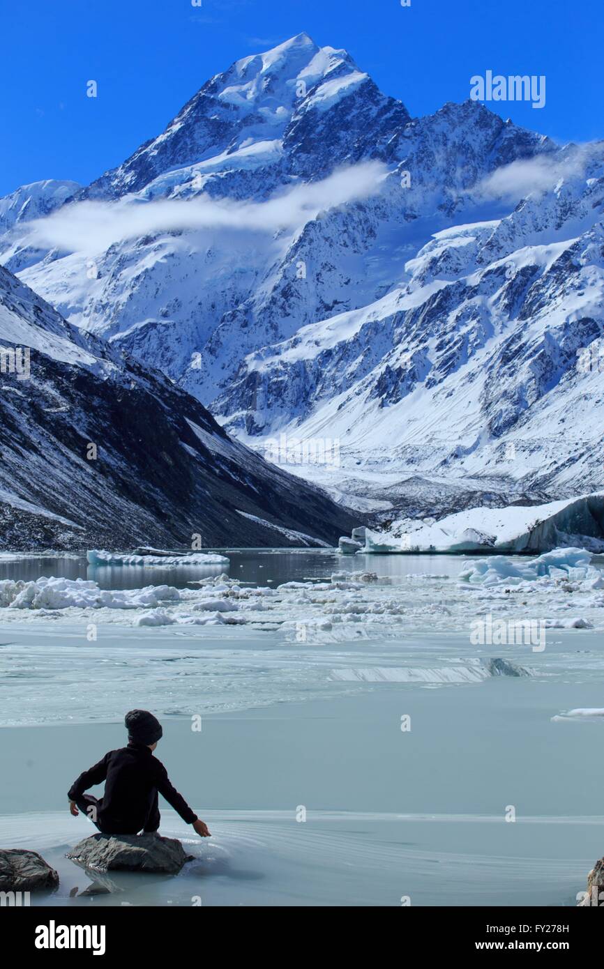A young boy plays with rocks on the edge of a glacial lake at the foot ...