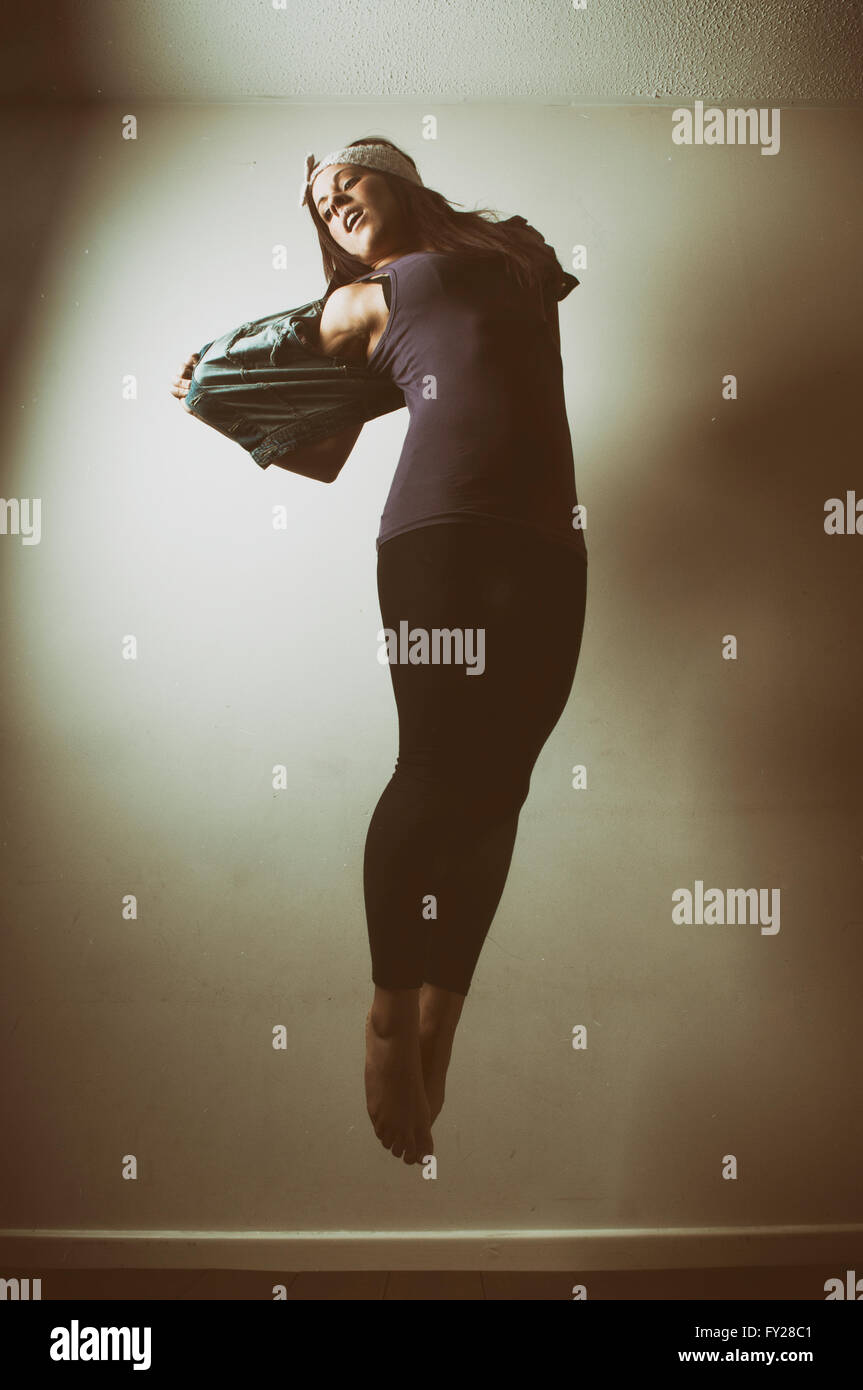 Young woman jumping inside a room Stock Photo - Alamy