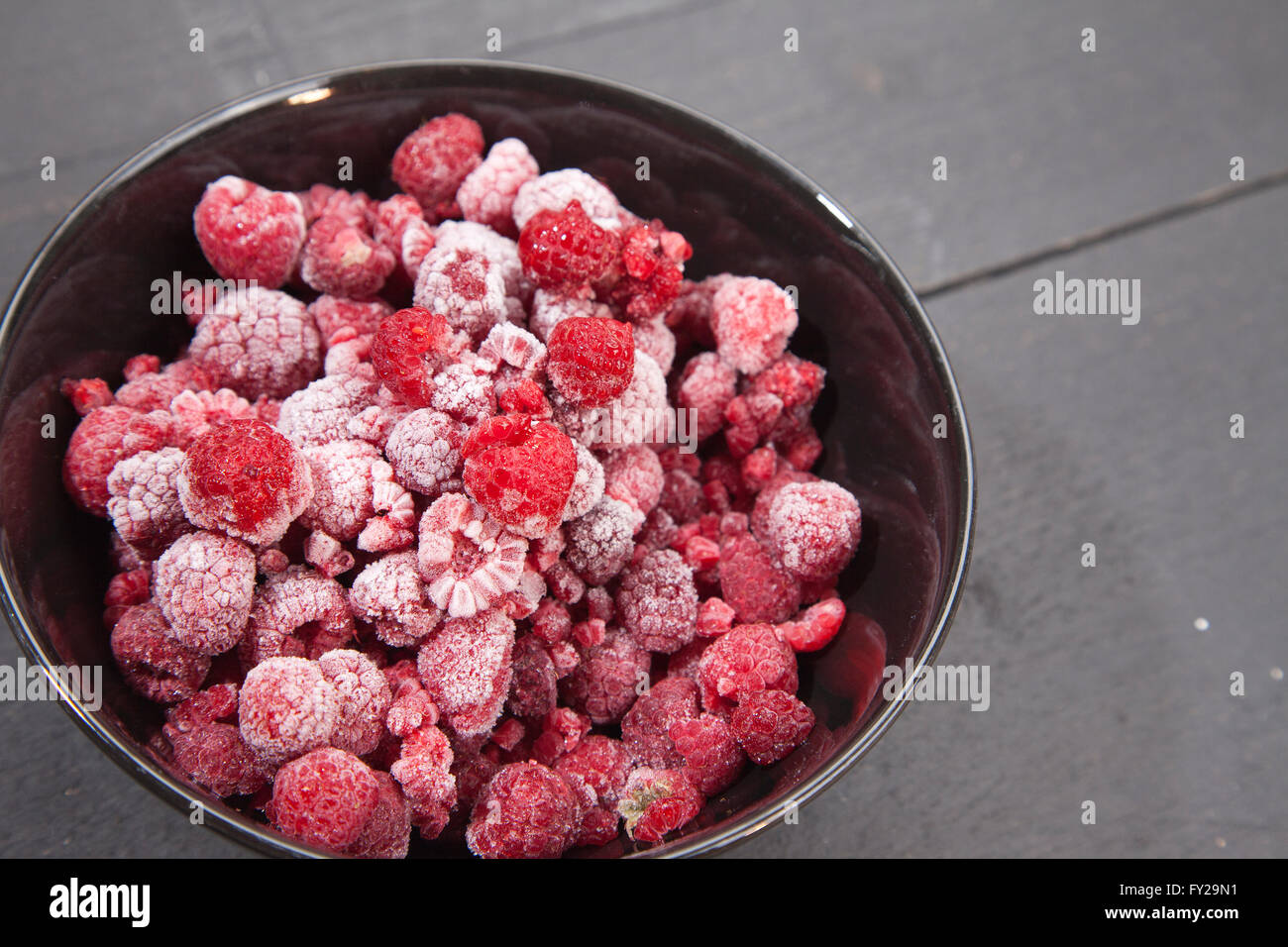 Frozen raspberries on dark wooden background Stock Photo - Alamy