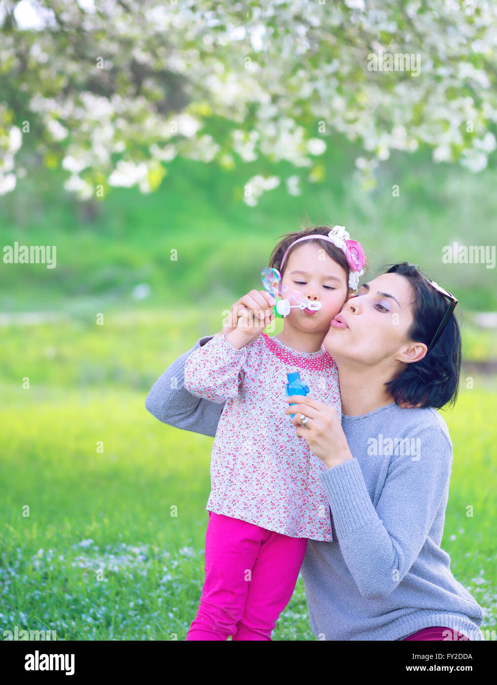 Happy young mother and her daughter blowing soap bubbles in park Stock ...