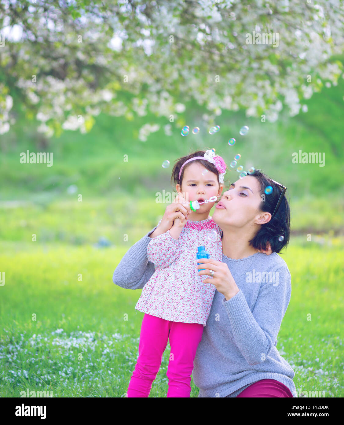 Happy young mother and her daughter blowing soap bubbles in park Stock ...