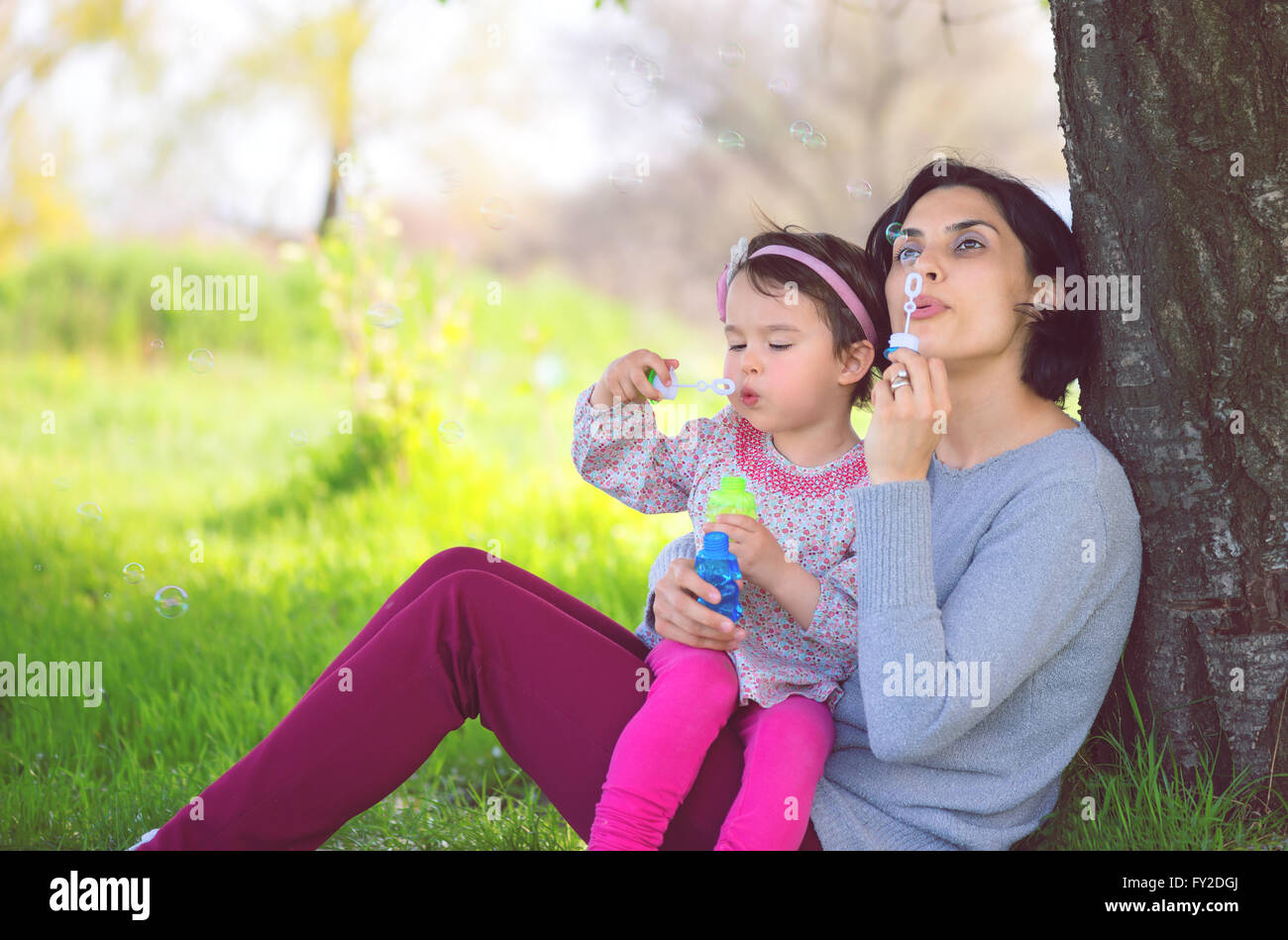 Happy young mother and her daughter blowing soap bubbles in park Stock ...