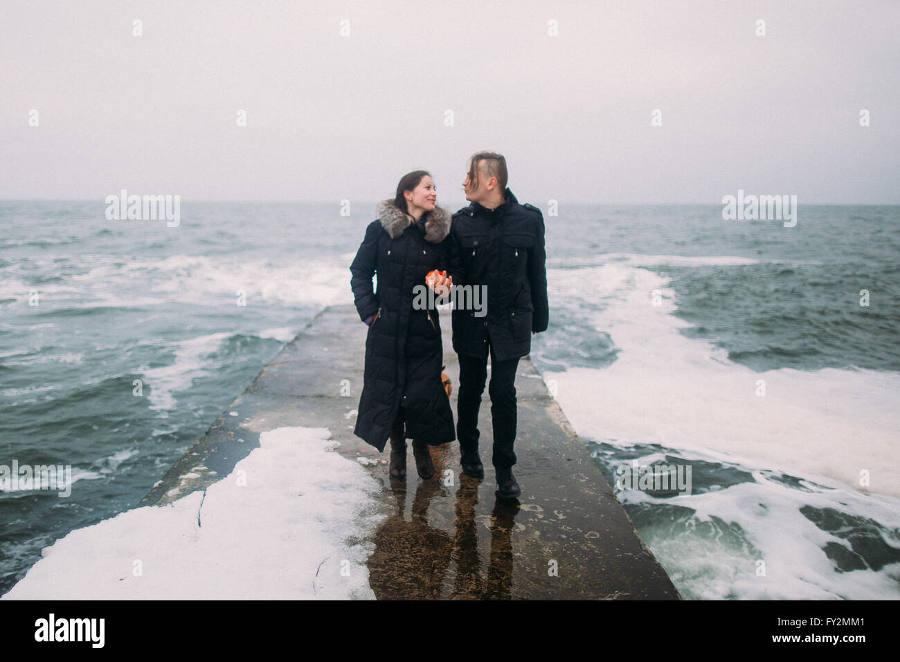 Happy young couple run towards each other on the old pier with ...