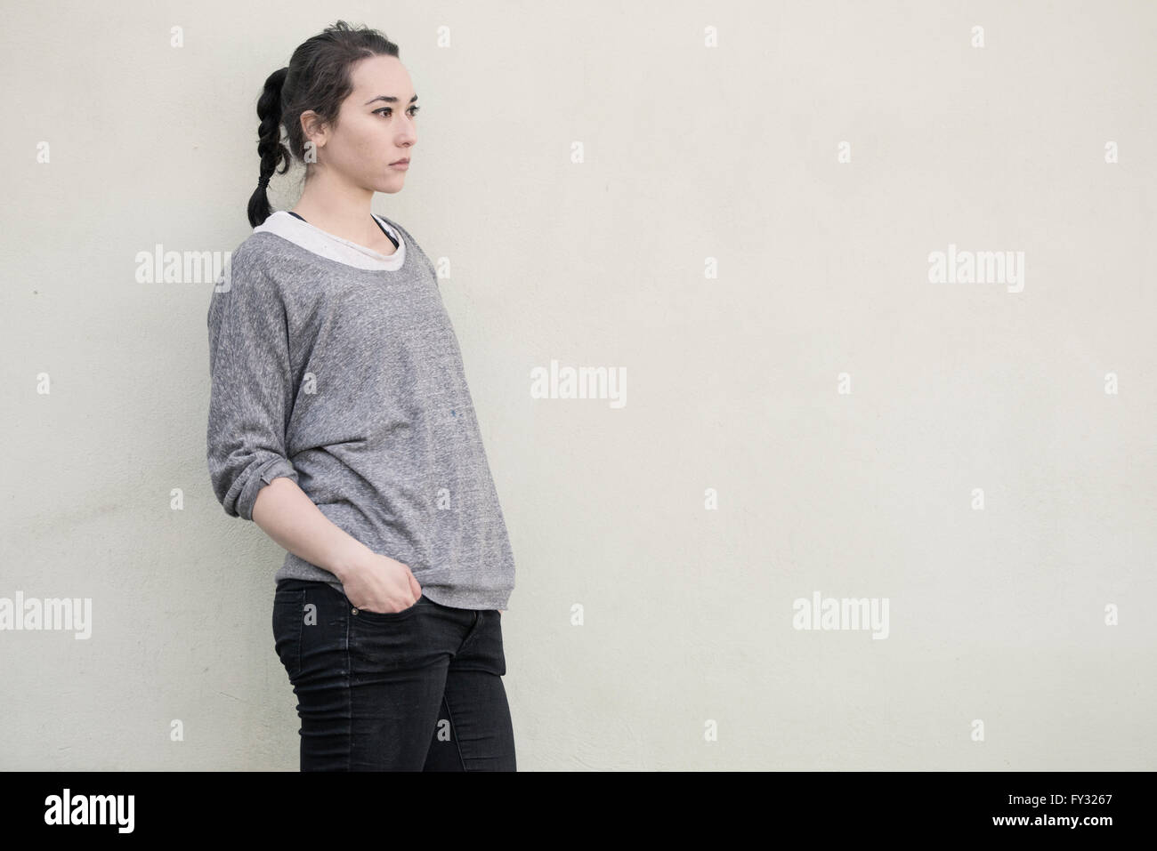 Young woman standing in front of wall Stock Photo - Alamy