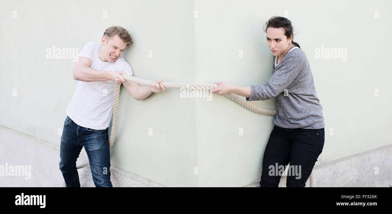 Angry couple pulling a rope from opposite sides of corner of house ...