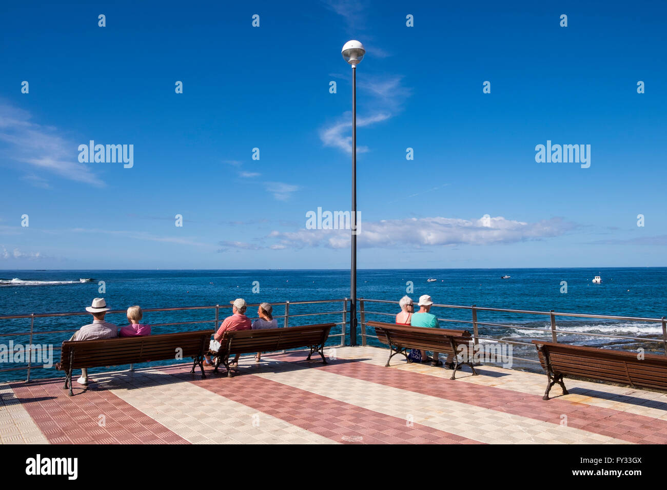 Visitors sitting and relaxing on benches at the Mirador viewpoint on the coast at La Caleta ...