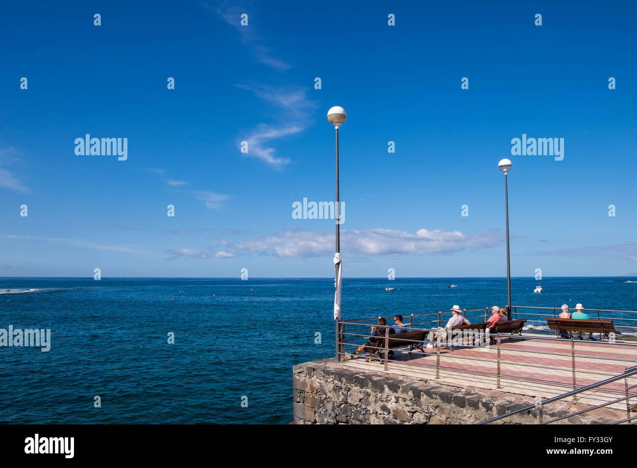 Visitors sitting and relaxing on benches at the Mirador viewpoint on the coast at La Caleta ...