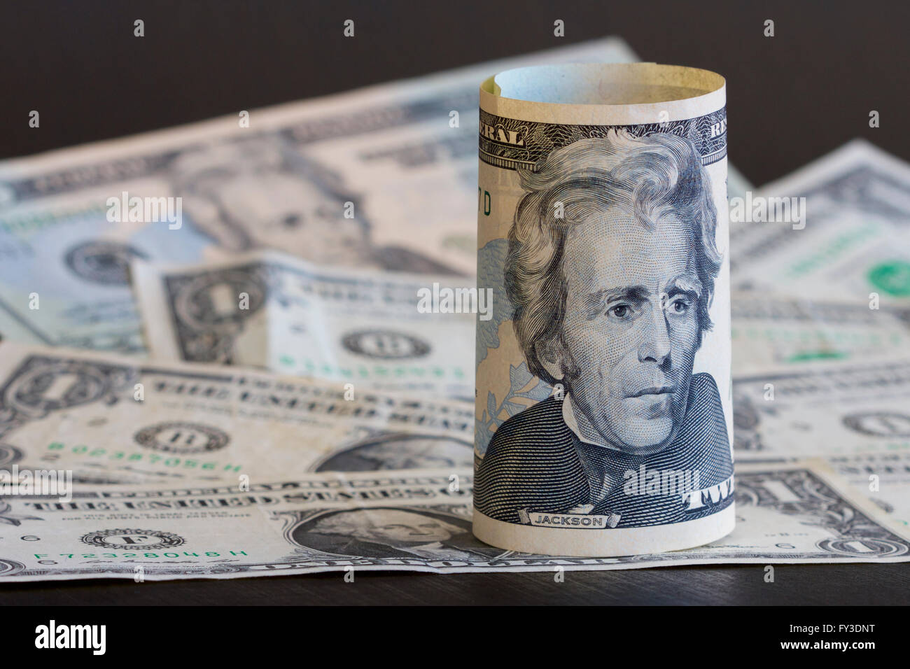 A roll of American dollars with a background of notes Stock Photo - Alamy