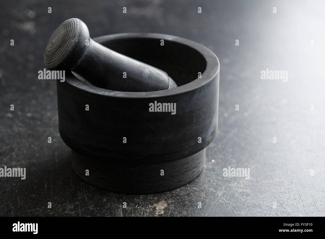 Black stone mortar on black kitchen table Stock Photo - Alamy