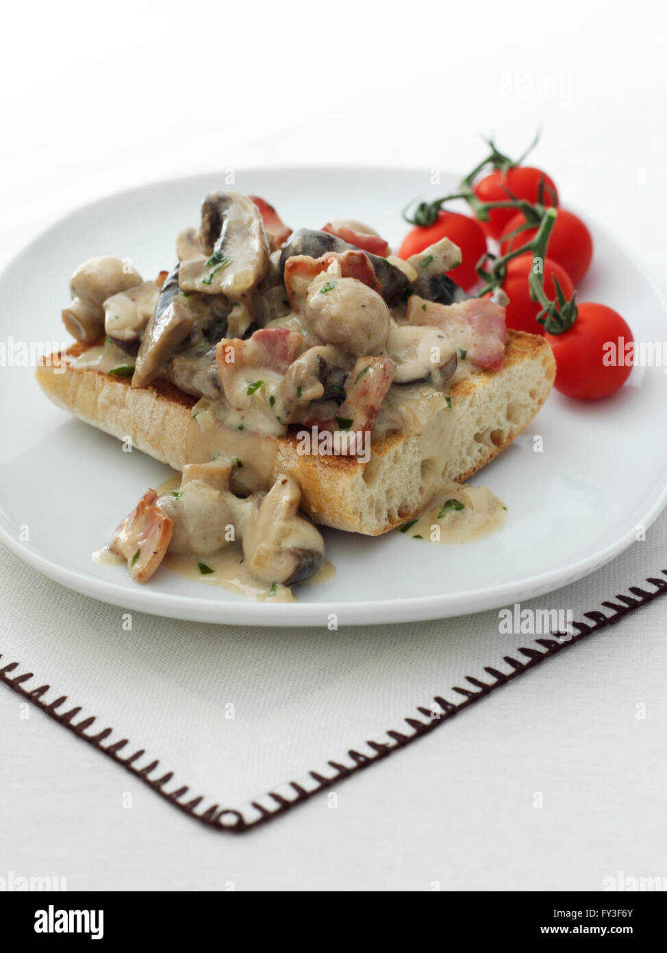 Toasted ciabatta topped with mushrooms and bacon in cream sauce, served ...