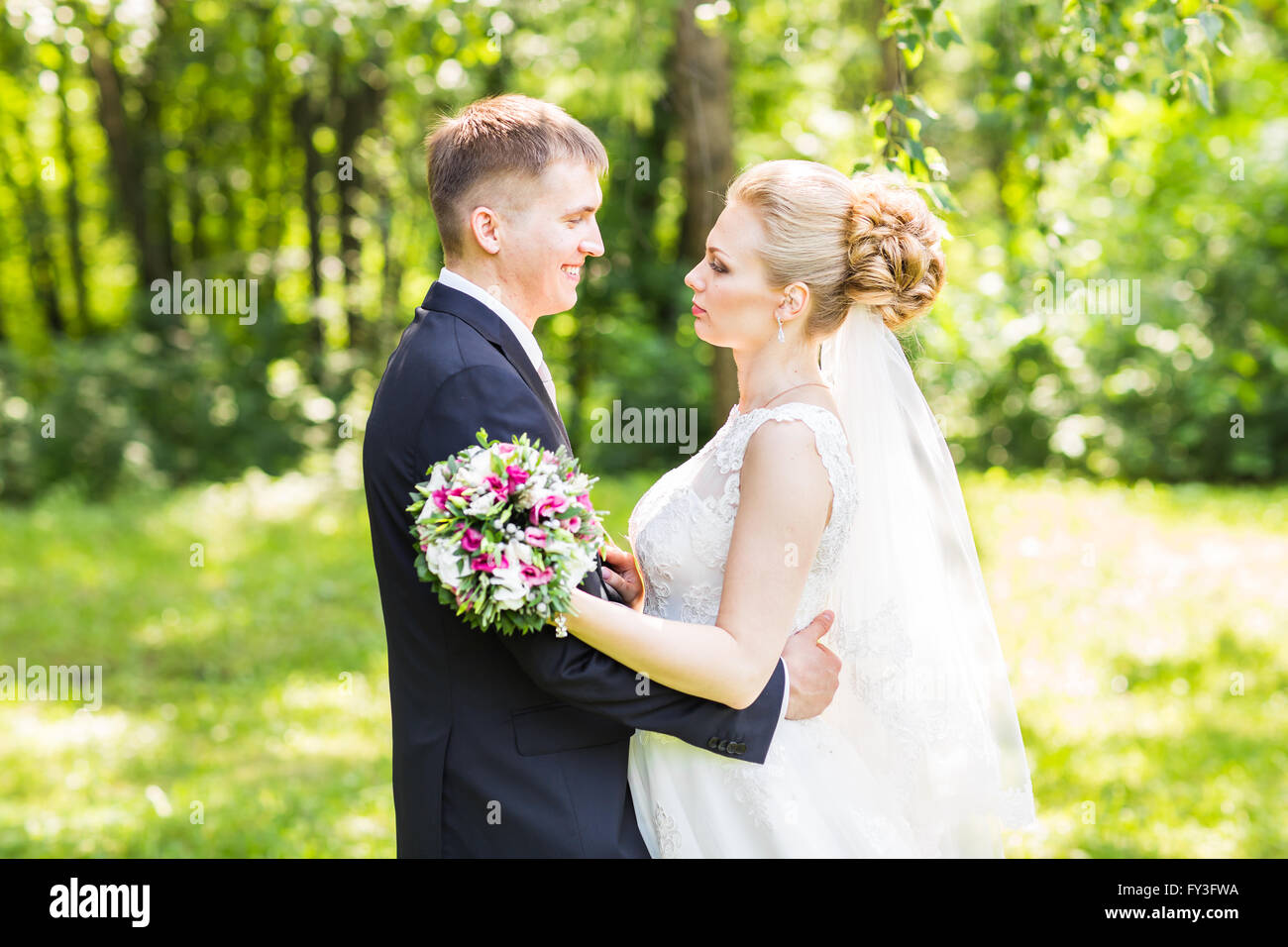 wedding couple hugging, bride holding a bouquet of flowers, the groom ...