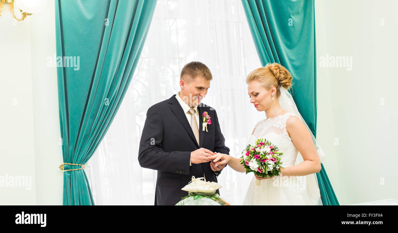 Groom slipping ring on finger of bride at wedding Stock Photo - Alamy