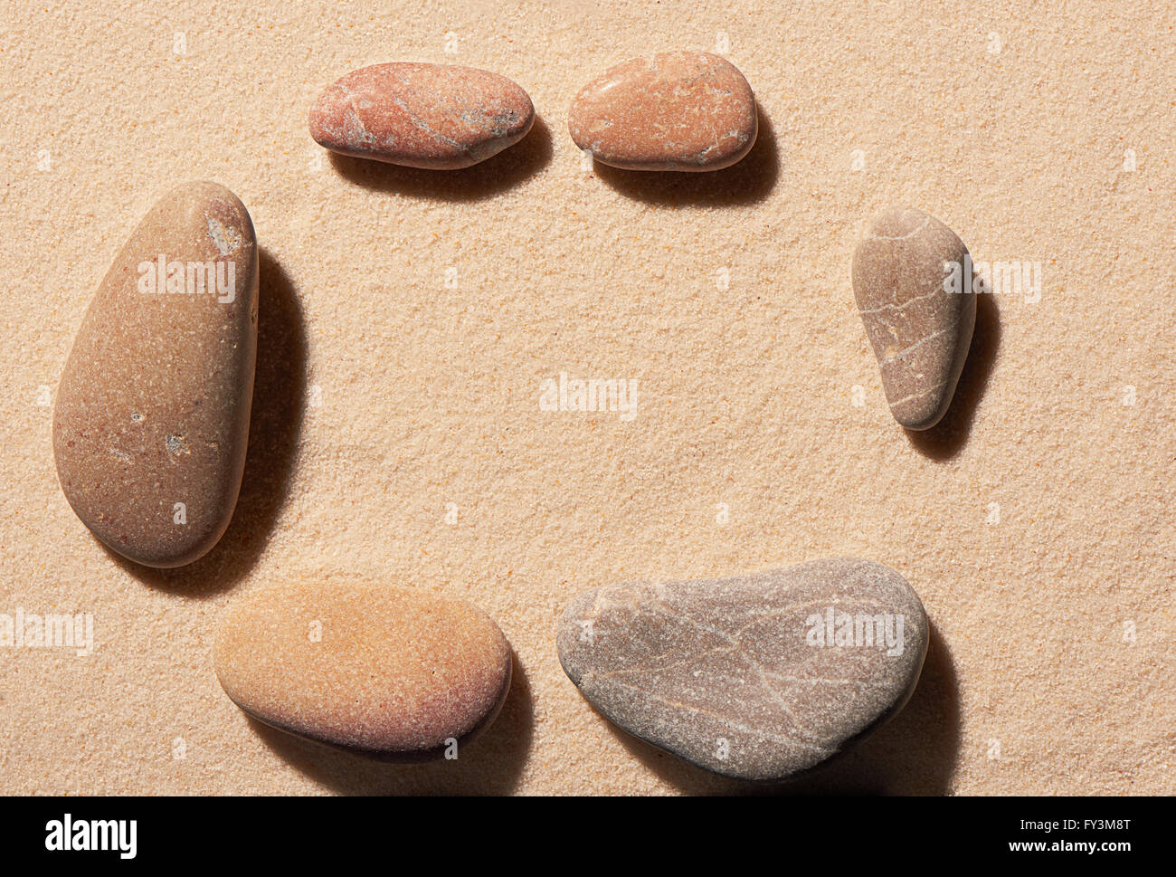 Rectangular frame of six small and large sea stones on sand. Summer ...