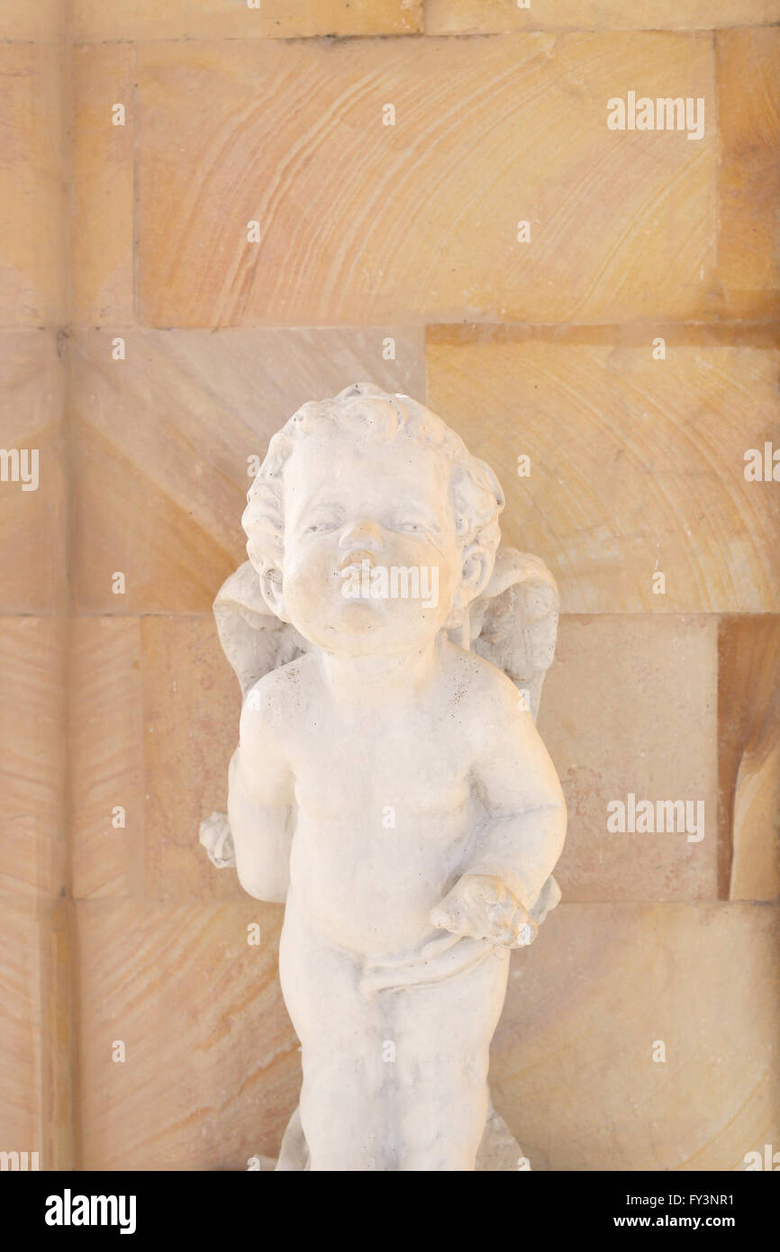 Old Cupid statue with have a backdrop is brown brick wall Stock Photo ...