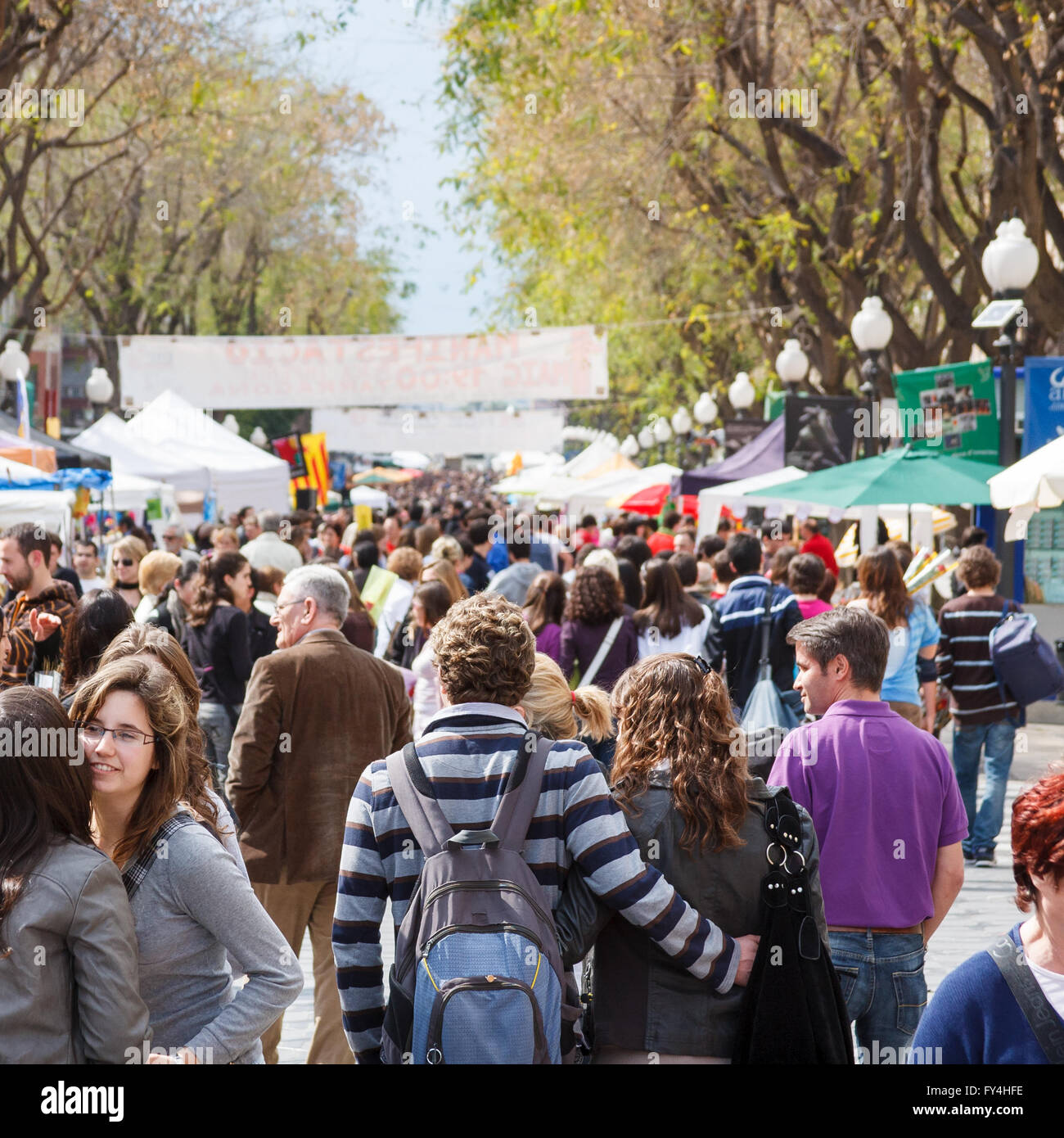 Rear view of couple with arms round each other on busy street in ...